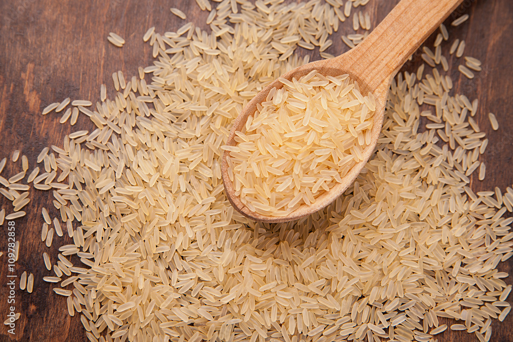 uncooked rice with spoon and woody background Stock Photo | Adobe Stock