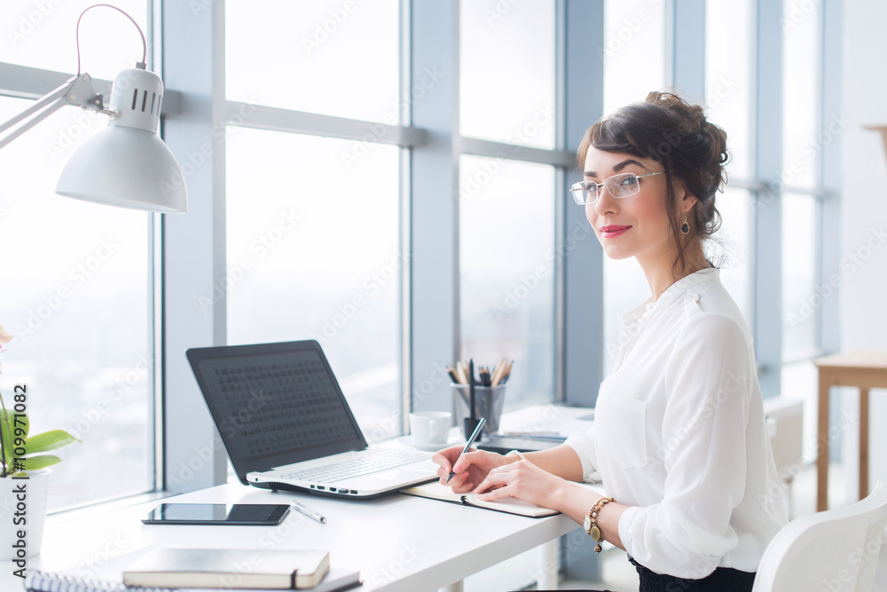 Portrait of a female writer working at office, using laptop, wearing ...