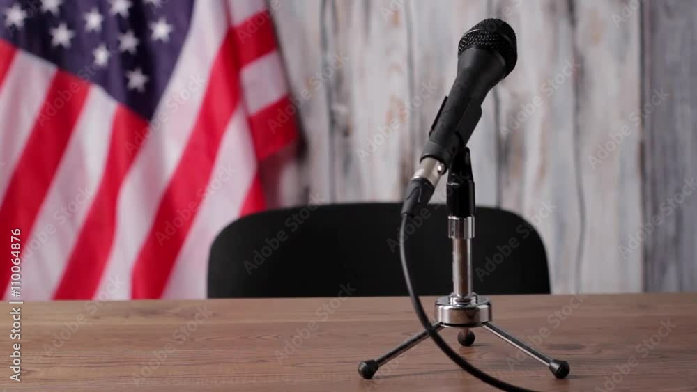 American flag, table and microphone. Banner behind desk with microphone ...