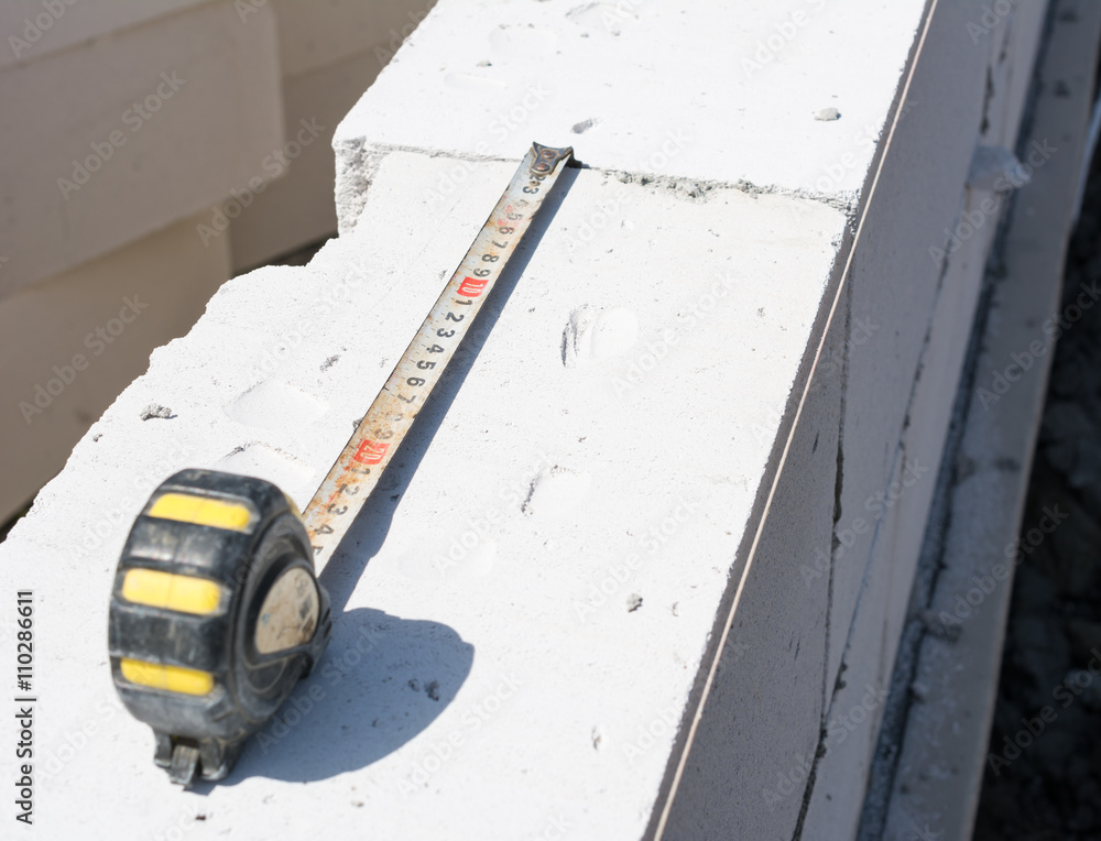 Yellow tape measure on white concrete blocks. Construction site concept ...