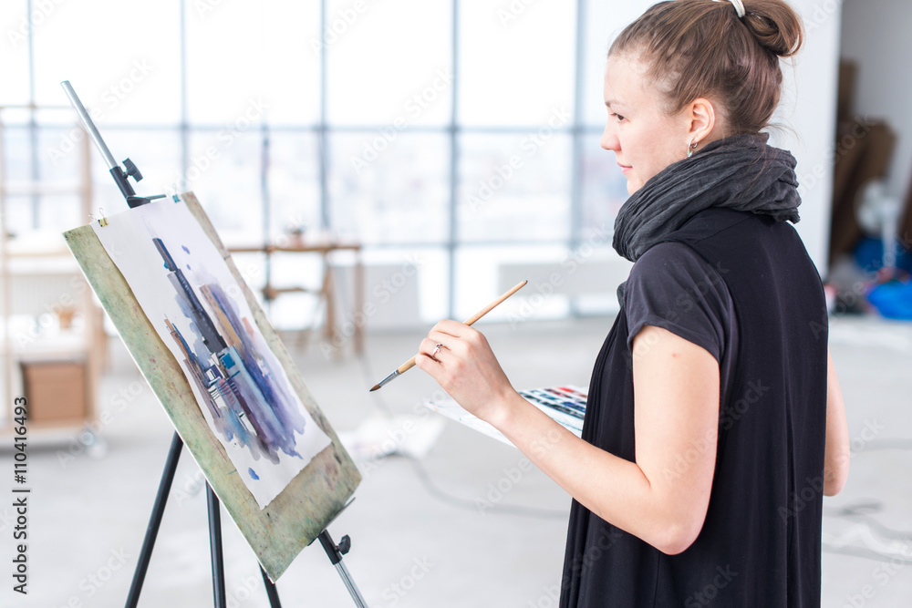 Female painter drawing in art studio using easel. Portrait of a young ...