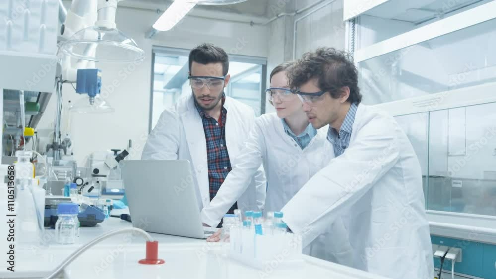 Group of Multiethnic Students in Coats using Laptop in Laboratory of Chemistry Classroom. Shot ...