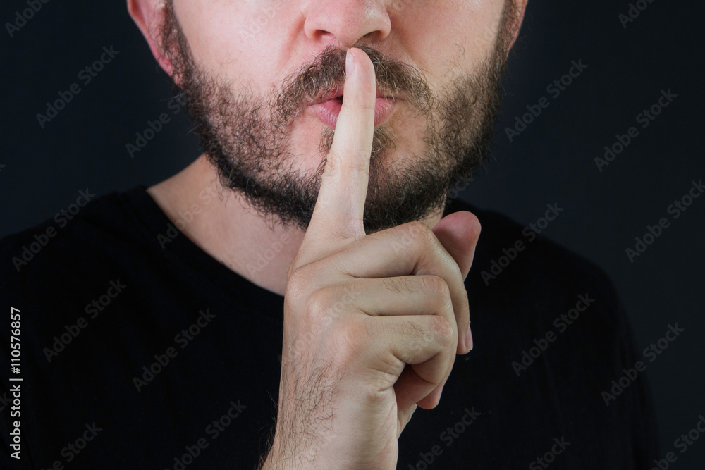 Serious man with beard and mustache making silence gesture, pst, shh ...