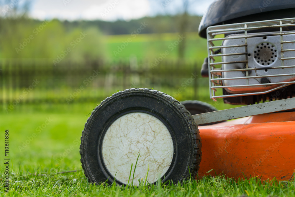 Detail of wheel and piece of motor of lawn mower (grass cutter) on ...