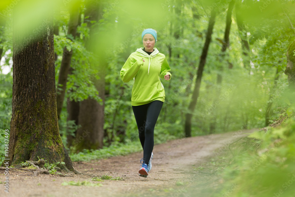Sporty young female runner in forest. Running woman. Female runner ...