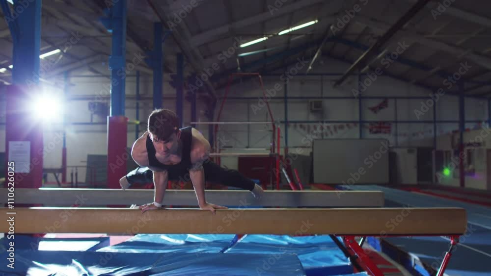 Male gymnast training on balance beam in dark gym Stock Video | Adobe Stock