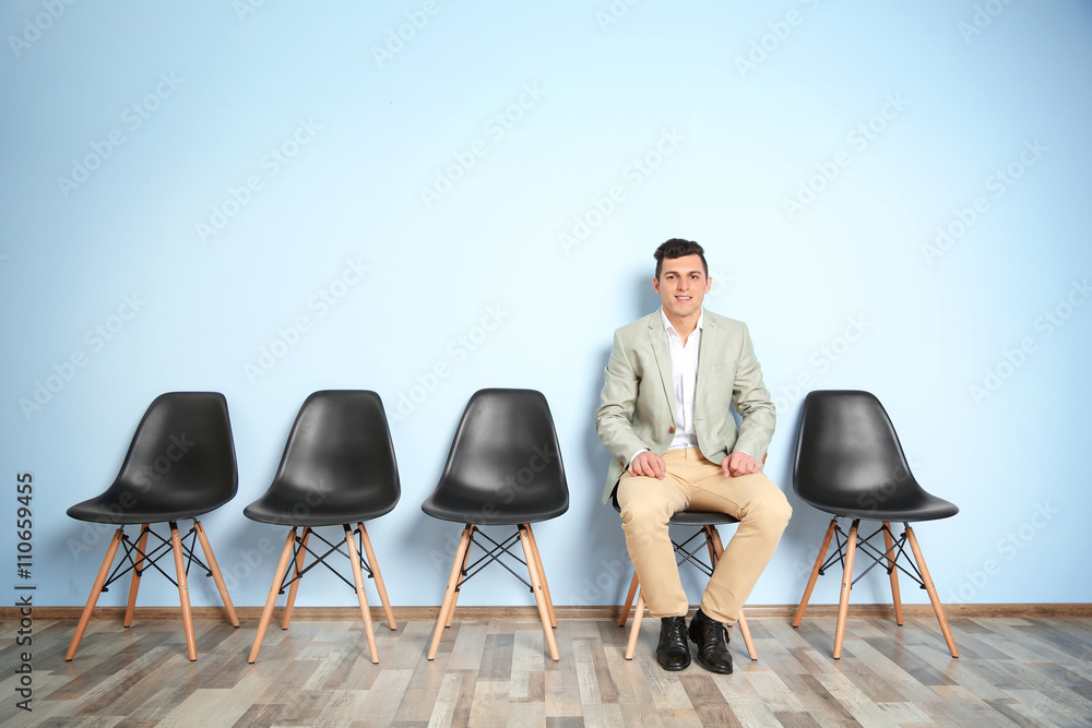 Young man in suit sitting on chair and waiting for job interview Stock ...