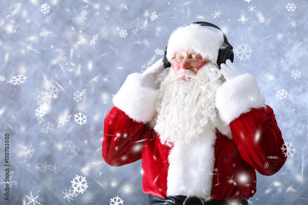 Santa Claus with headphones listening to music on gray wall background ...