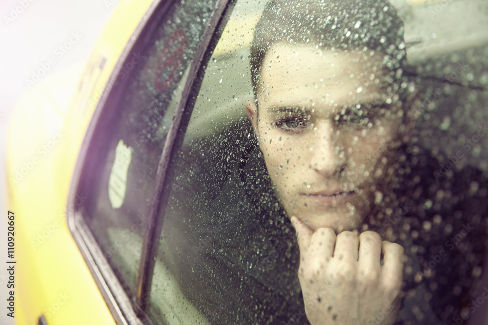 Young man gazing out of yellow cab window in rain Stock Photo | Adobe Stock