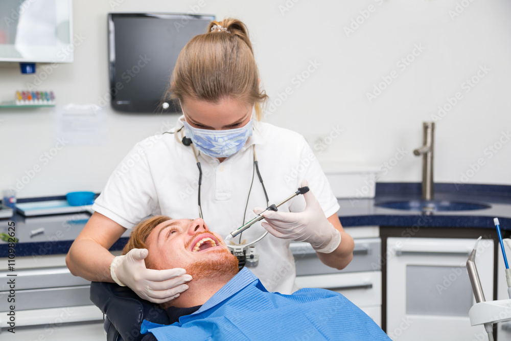 Dentist giving patient injection for anesthetization in dental clinic ...