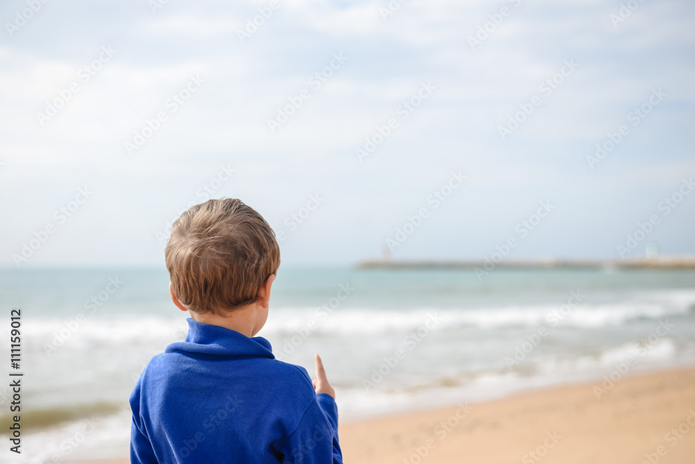 Back view portrait of cute boy at the beach on ocean background ภาพถ่าย ...
