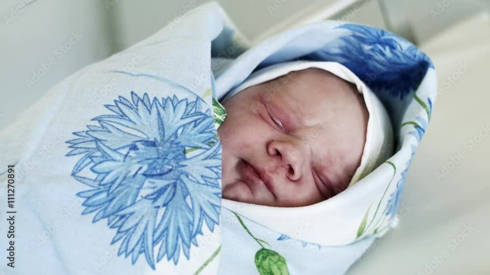 Swaddled newborn baby open eyes, lay on table in maternity hospital in ...