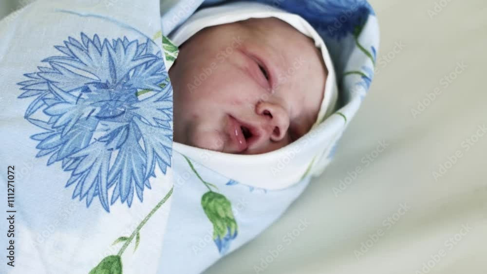Swaddled newborn baby open eyes, squint from daylight, yawning. Lay in ...