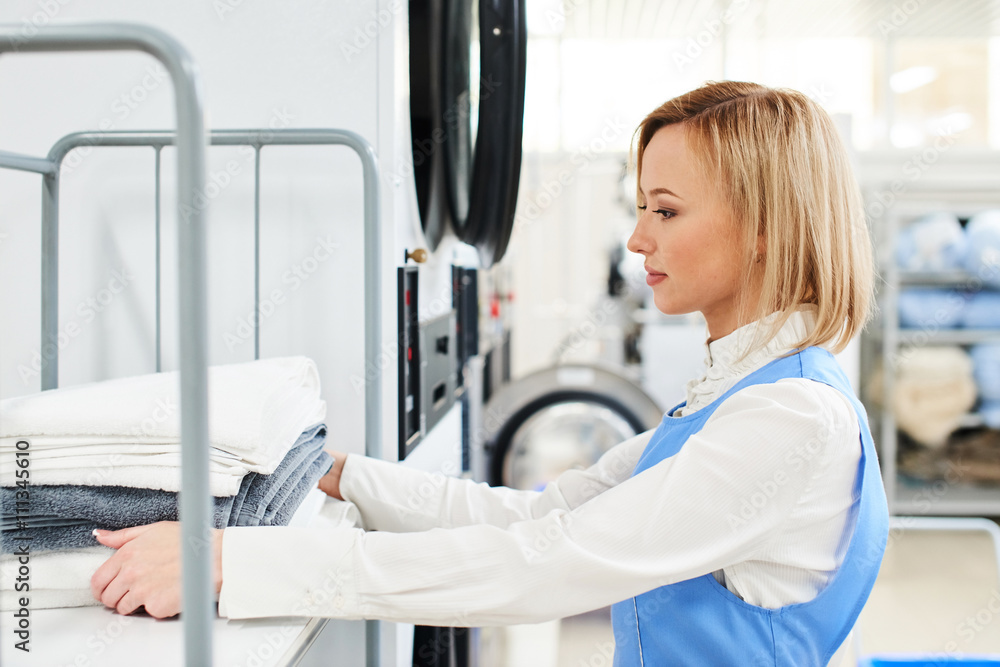 Girl Laundry worker puts clean clothes on the shelf at the dry cleaners ...