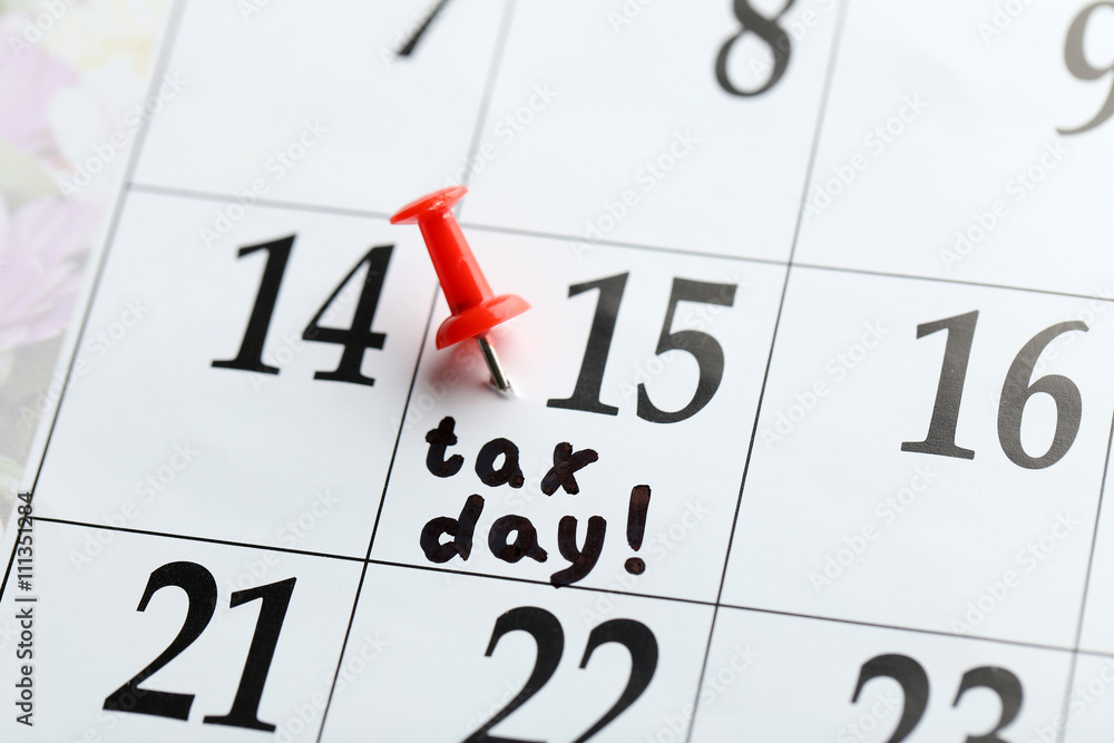 Tax day written and pinned in a calender on date of 15th, close up ...