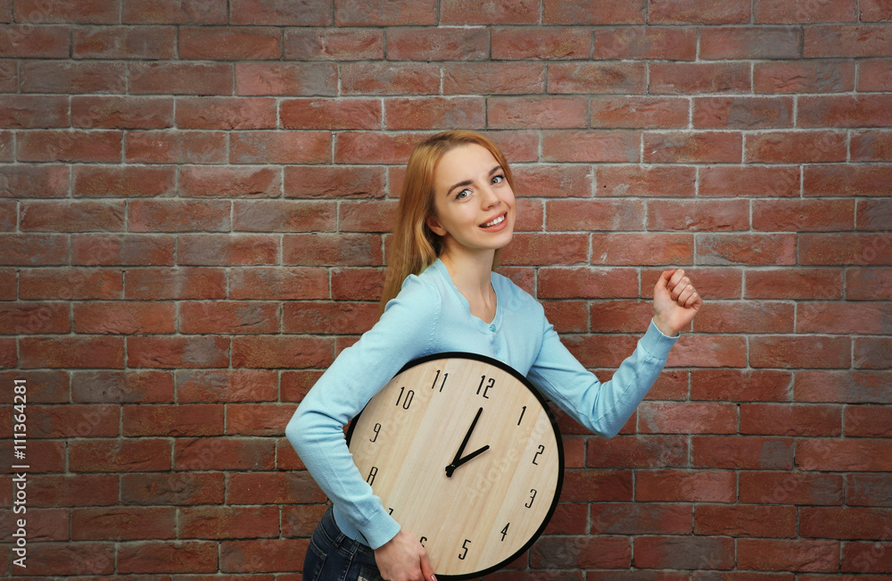 Young beautiful woman holding clock against brick wall background Stock ...