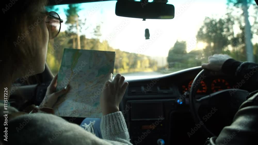Woman holding map and showing the route map to her boyfriend driving ...