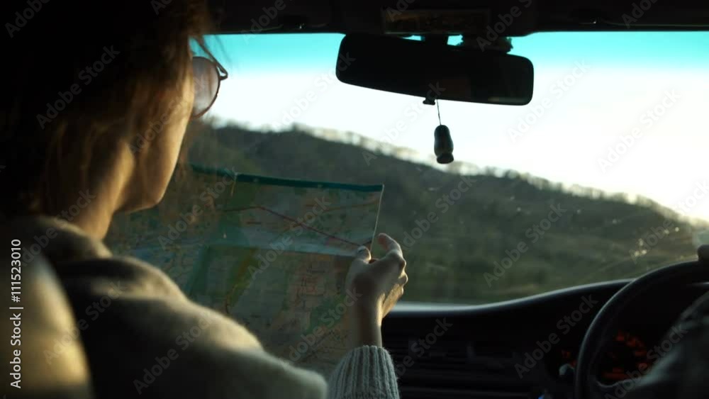 Woman holding map and showing the route map to her boyfriend driving ...