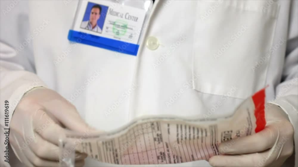 A laboratory technician cuts open a plastic bag and removes a glass ...