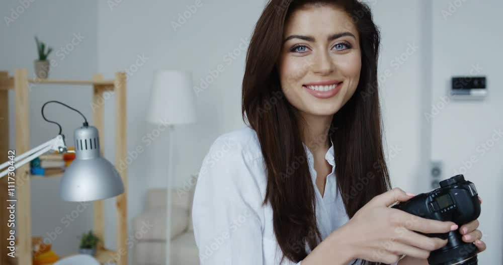 Side view of attractive smiling brunette female photographer in white ...
