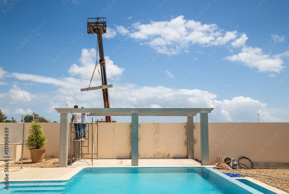 Pool side construction of a pergola. A crane can be seen lowering a ...