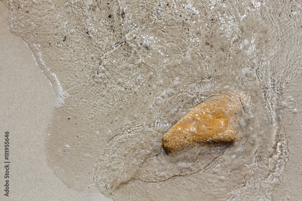 The sand under the water. A lone Golden stone. Beige texture. Can be ...