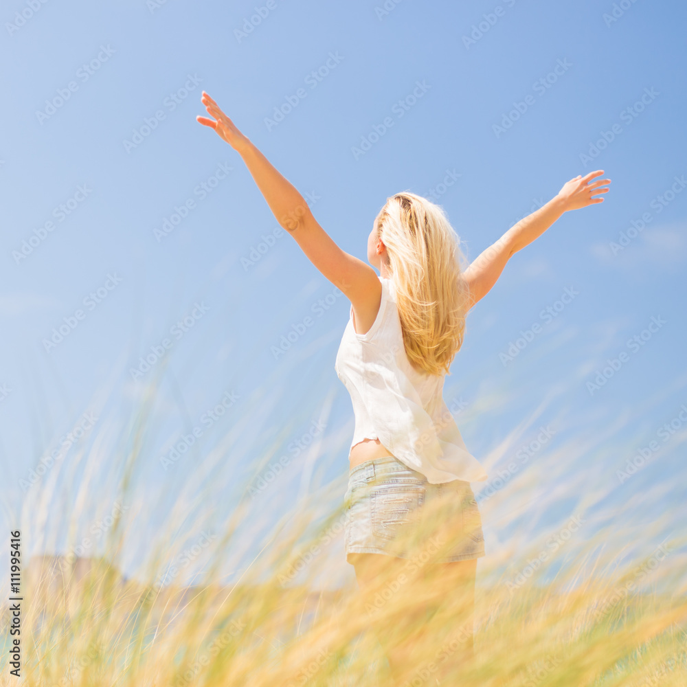 Relaxed woman, arms rised, enjoying sun, freedom and life an a ...