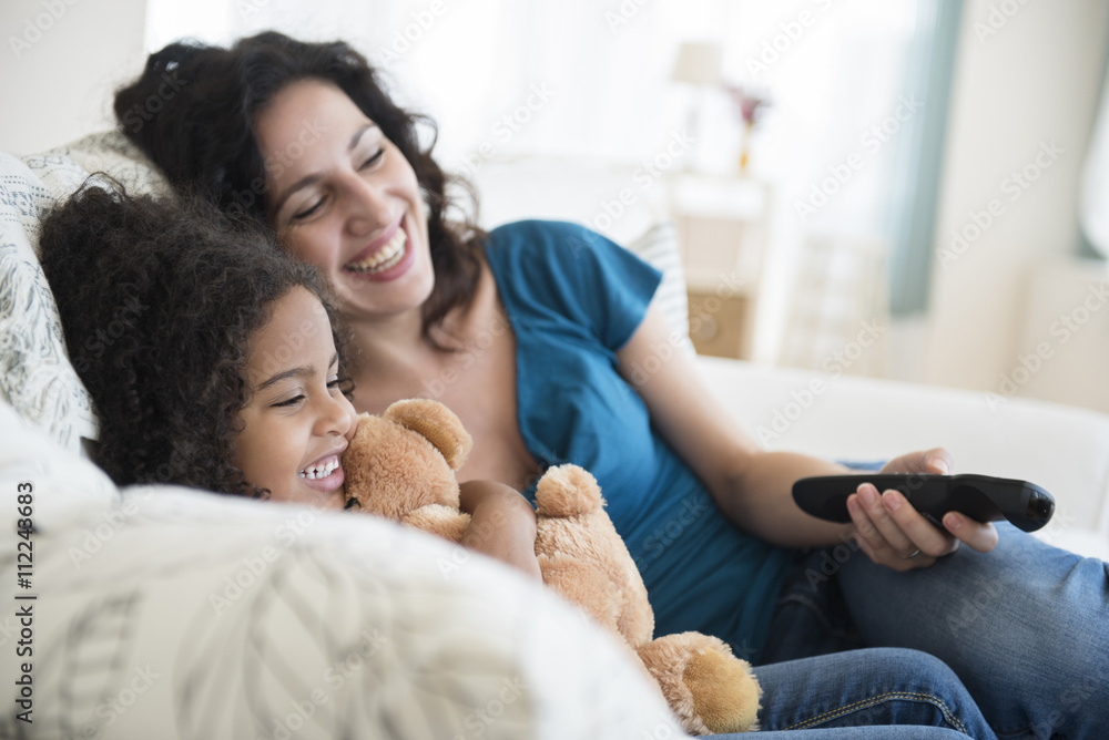 Mother and daughter watching television on sofa Stock Photo | Adobe Stock