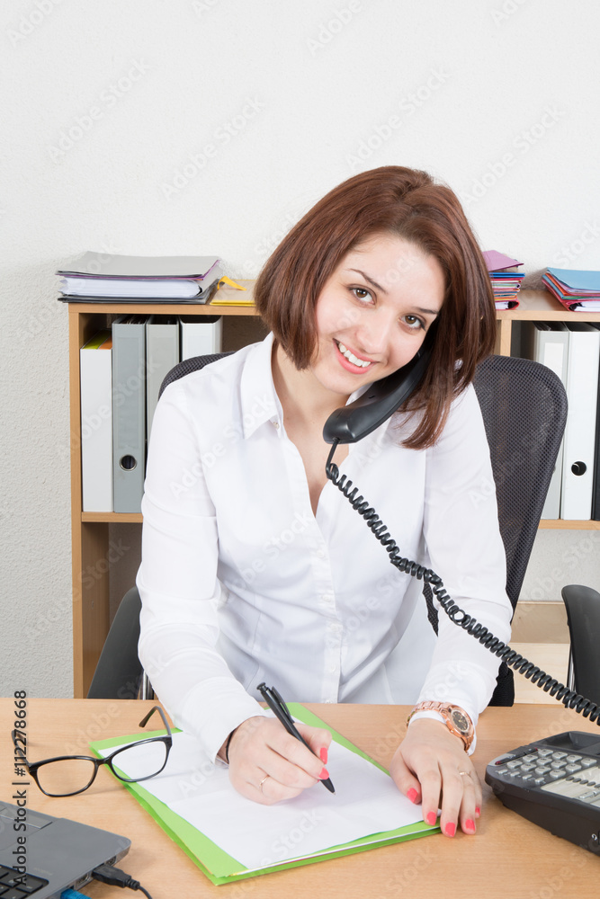 Cute office girl at desk using landline phone, smiling. Stock Photo ...