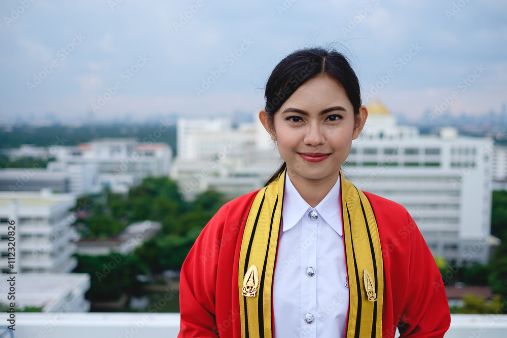portrait of thai graduated young adult woman in red and golden uniform ...