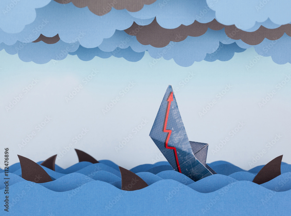 Paper boat is sinking into paper sea. Paper waves, clouds and sharks ...