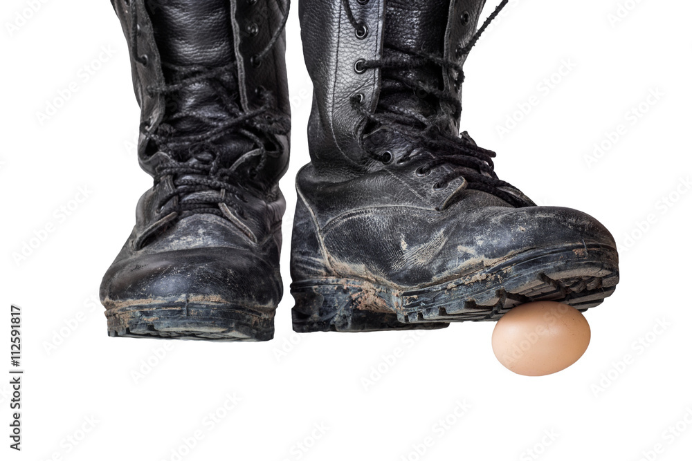 Old black army boots trampling egg. The egg as a symbol of the ...