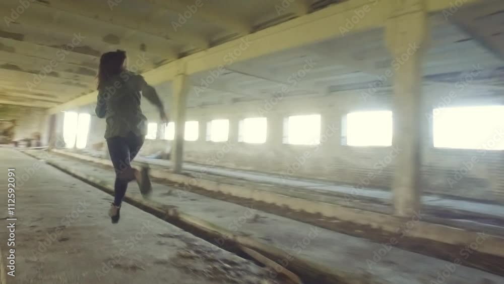 The girl run away from killer in abandoned building through the hallway ...