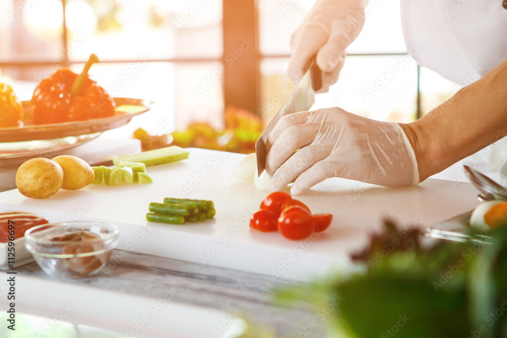 Hand with knife cuts egg. Sliced asparagus and tomatoes. Hands of chef ...