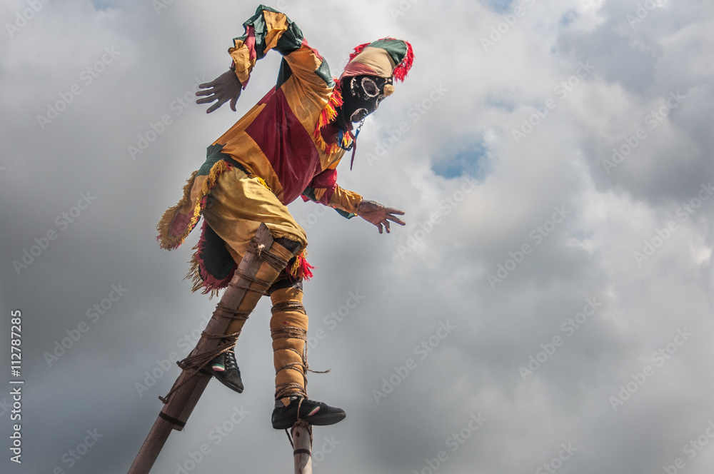 Man in jester costume balancing on stilts Stock Photo | Adobe Stock