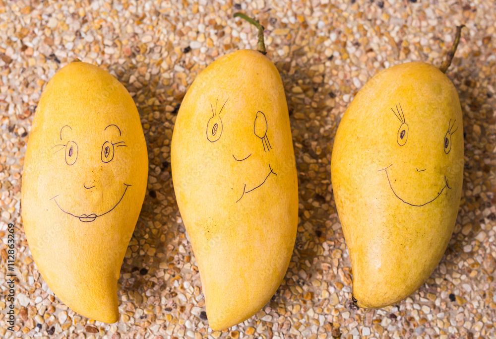 Drawn smiley face on a mango fruit. Fruits, diet, healthy food concept ...