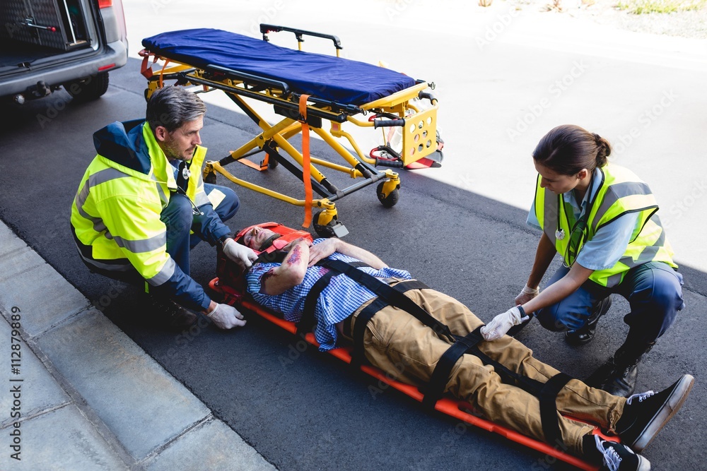 Ambulancemen carrying injured man on a stretcher Stock Photo | Adobe Stock
