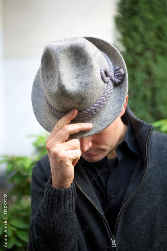 Fotografia do Stock: Man holding two fingers and thumb on grey hat ...