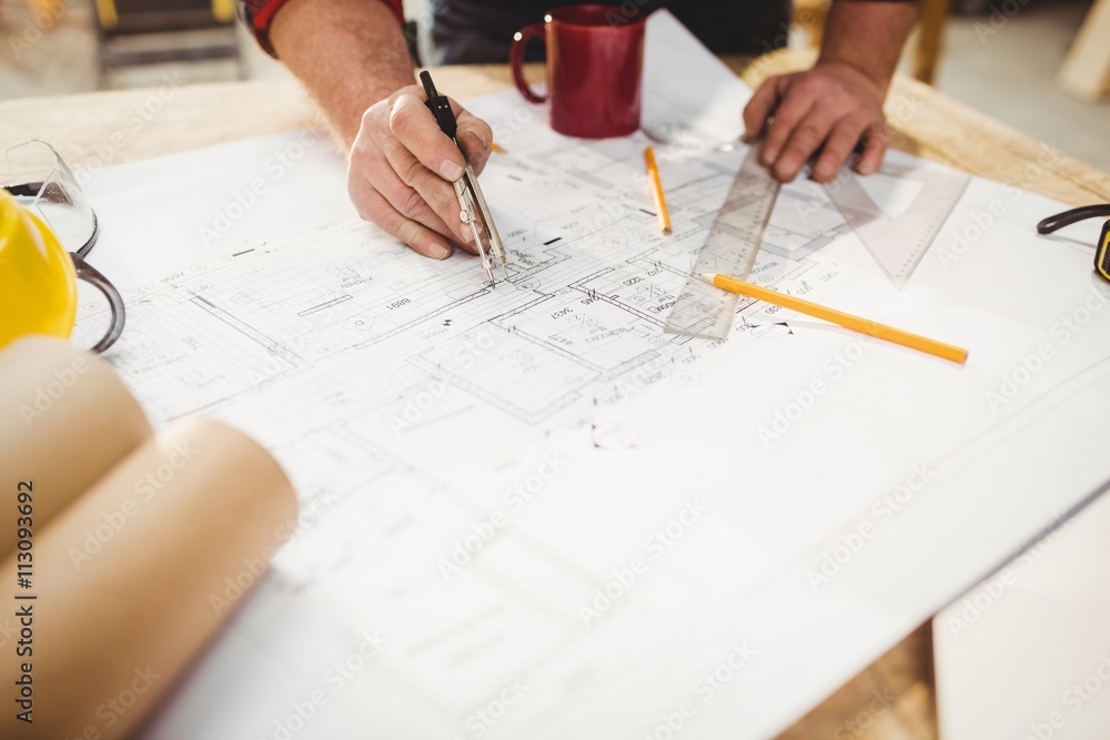 Carpenter drawing on a plan with a compass Stock Photo | Adobe Stock