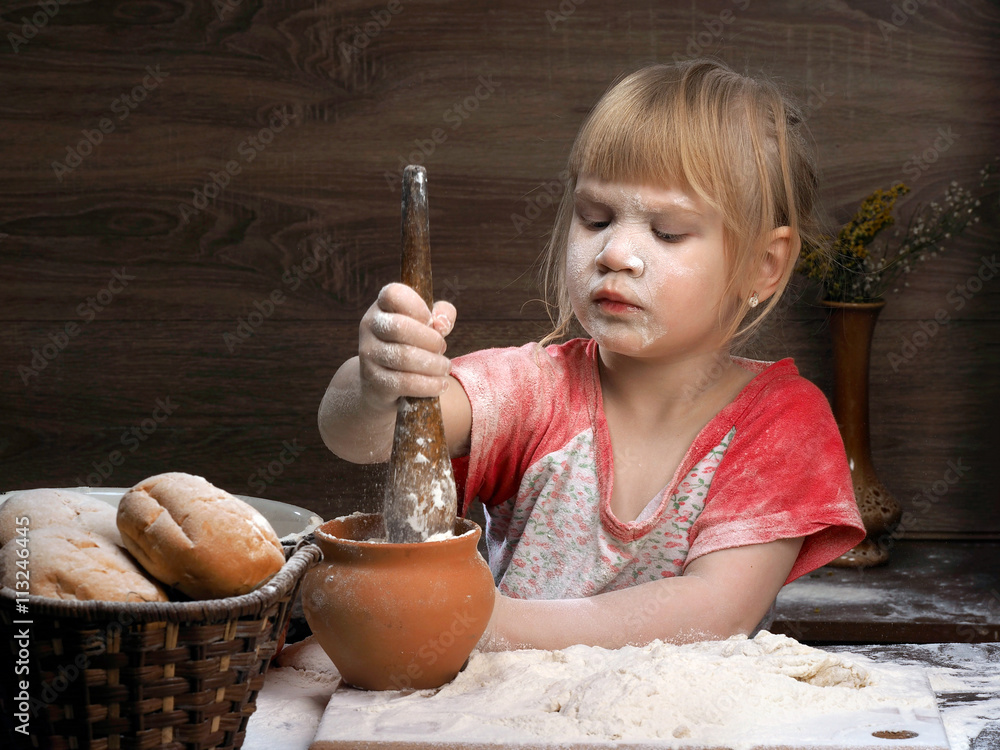 A child plays with the flour. Girl knead the dough. Girl funny stained ...