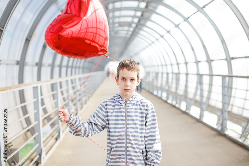 sad boy with a red heart in the hands. love-lorn. child standing with a ...