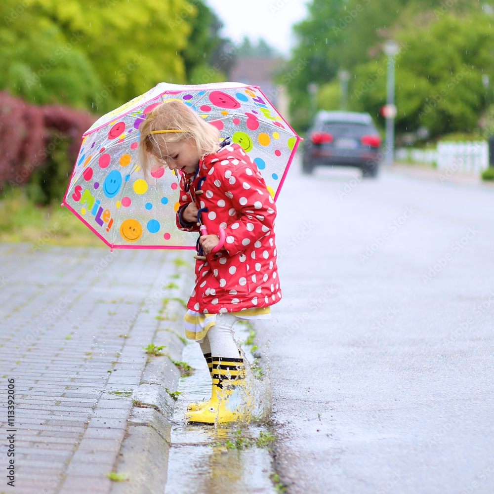 Happy little child playing on the street during rainy day. Adorable ...
