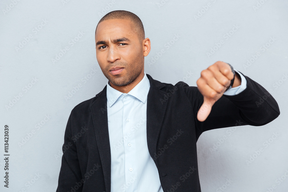 Young guy showing thumbs down sign over gray background Stock Photo ...