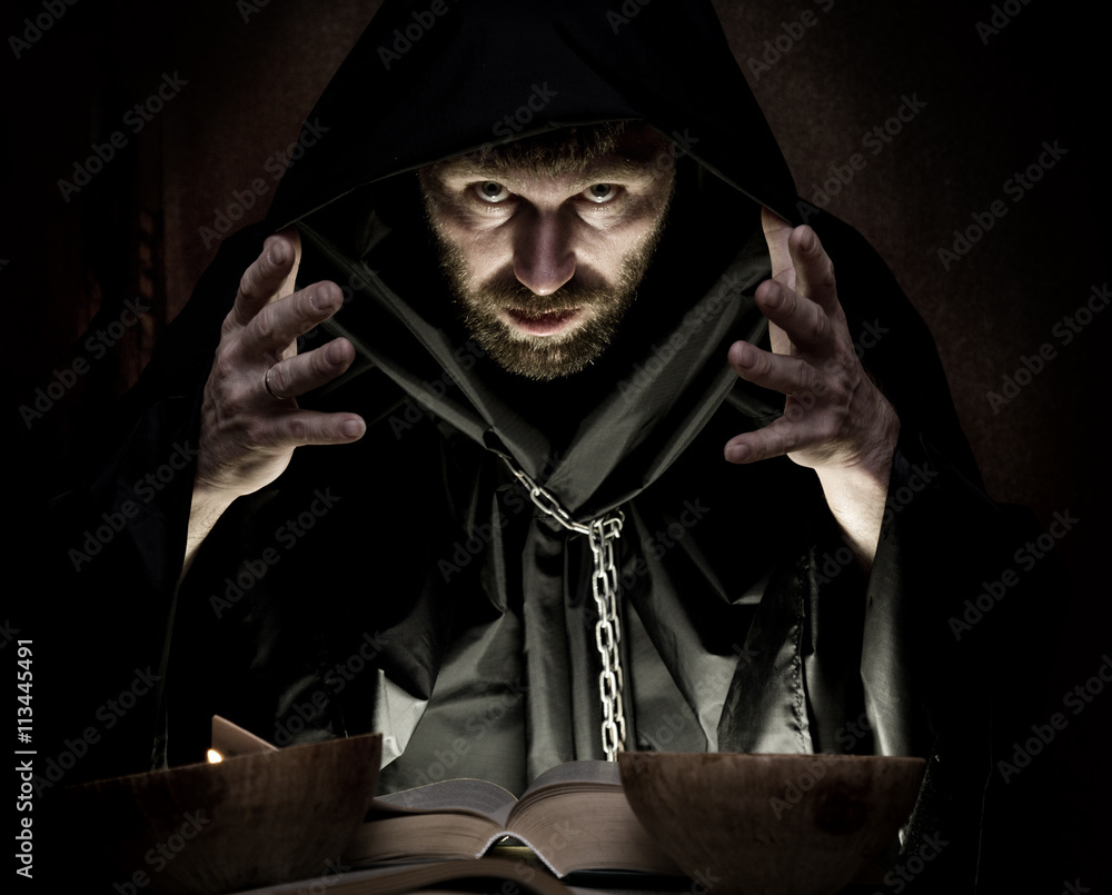 necromancer casts spells from thick ancient book by candlelight on a ...