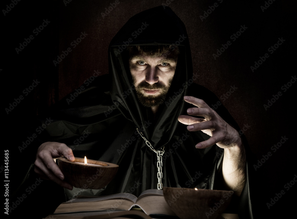 necromancer casts spells from thick ancient book by candlelight on a ...