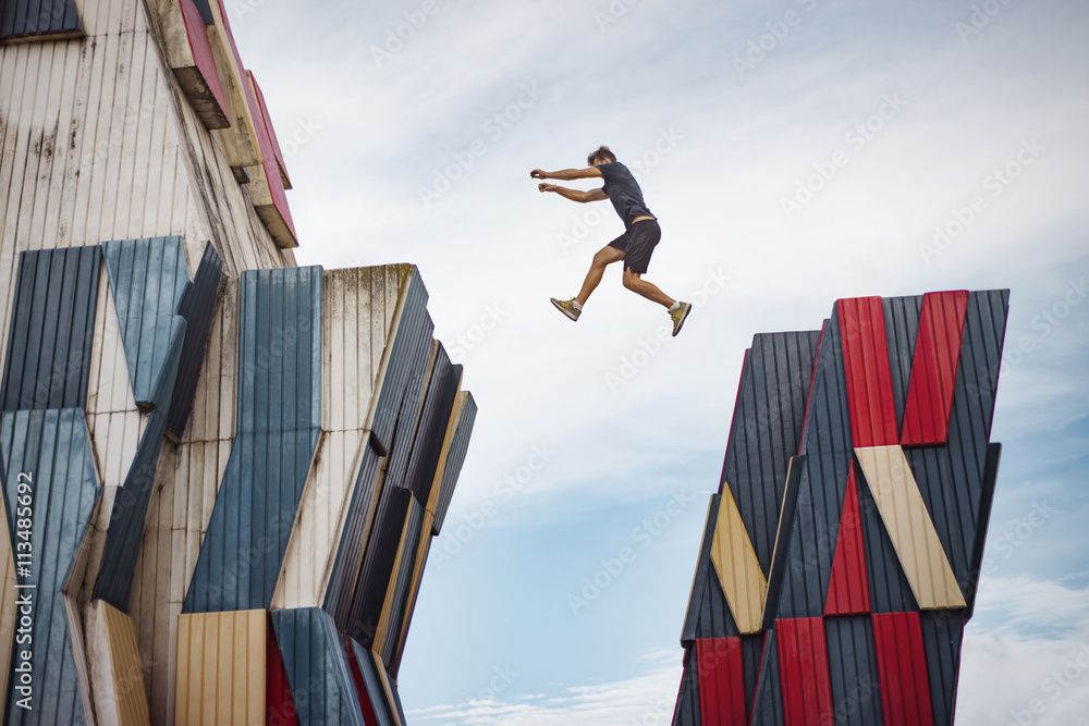 Man jumping over a gap between two buildings foto de Stock | Adobe Stock