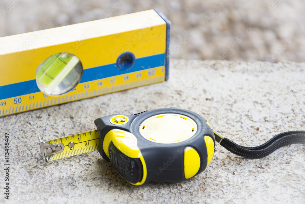 Tape measure and used level tool on brick with background rock nature ...