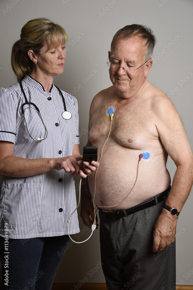 ENGLAND UK - JUNE 2016 - Member of a hospial cardiac measurement team installing a ambulatory ...