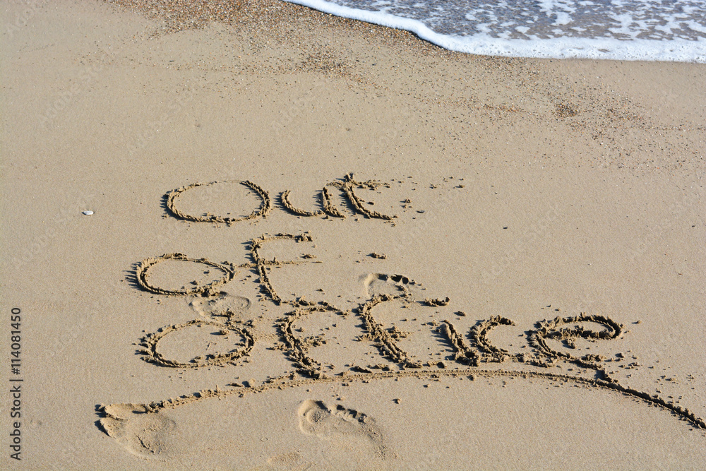 Out of office text written in sand on a beach suggesting work life ...