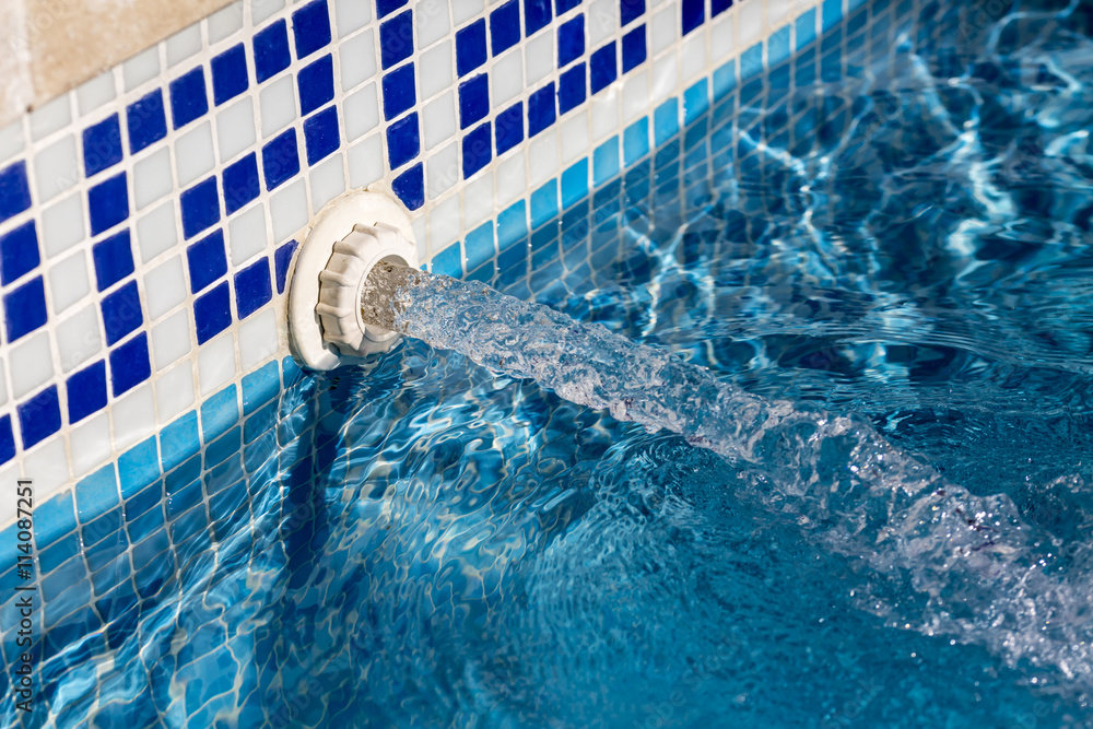 Detail view of a inflowing water jet into a swimming pool with blue ...